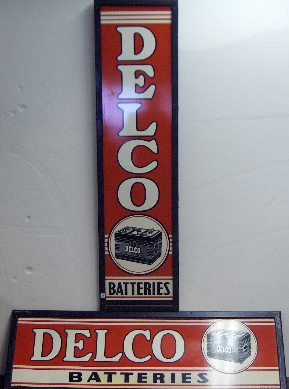 Bonhams Cars : Two Delco Batteries advertising signs, circa 1946, the larger 70 x 18in