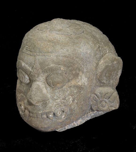 Bonhams : A Southeast Asian carved stone head of a ferocious deity