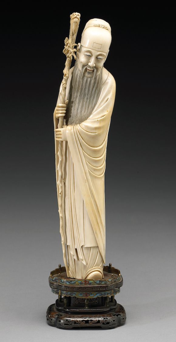 Bonhams : A tinted ivory figure of a standing Daoist immortal holding a ...