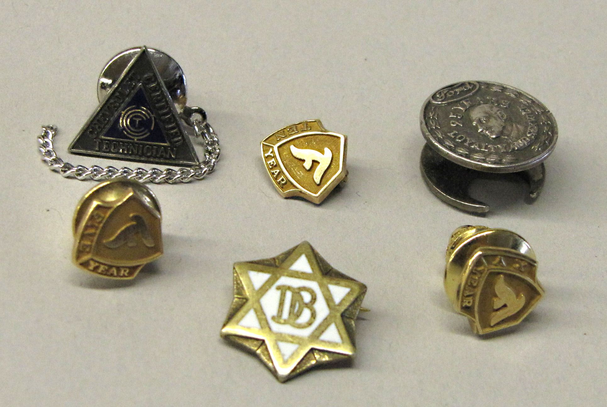 Bonhams Cars : A set of three gold Firestone long service lapel badges,