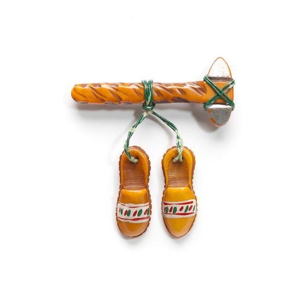 Bonhams : A Bakelite hand painted tomahawk and moccasin brooch